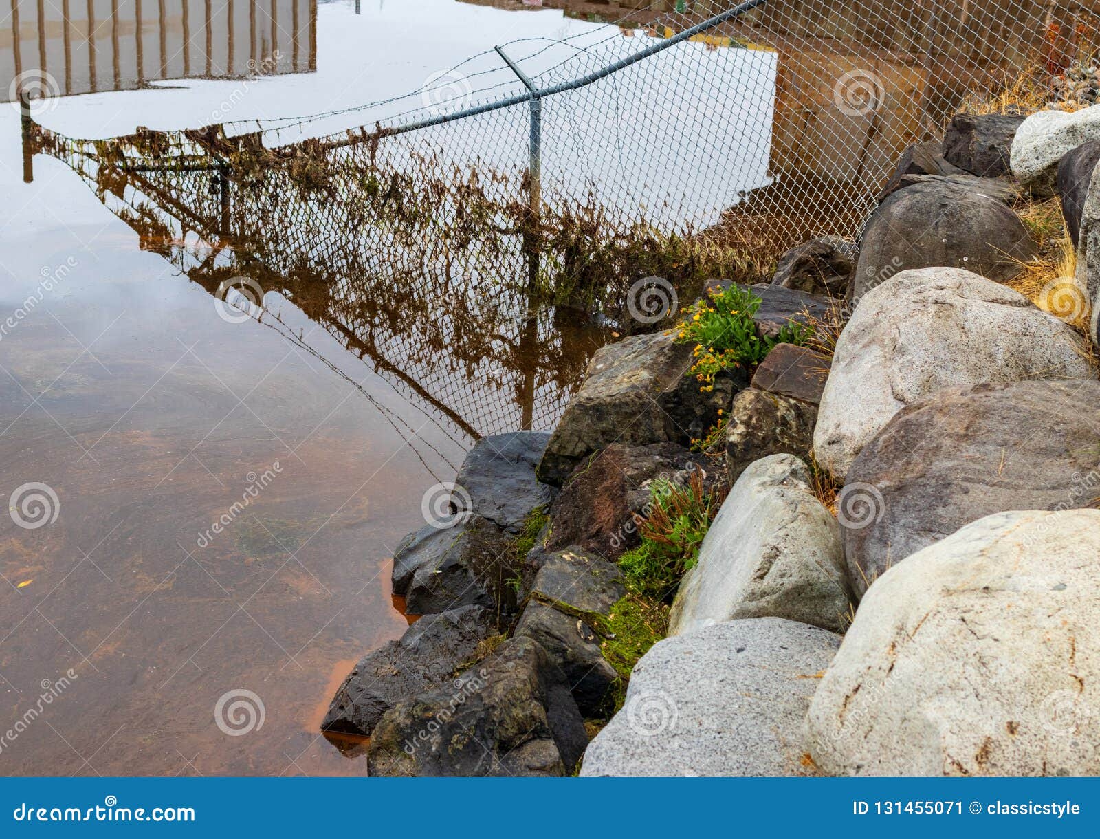 Fence Submerged in Tidal Water with Grass and Debris by a Rocky Shore ...