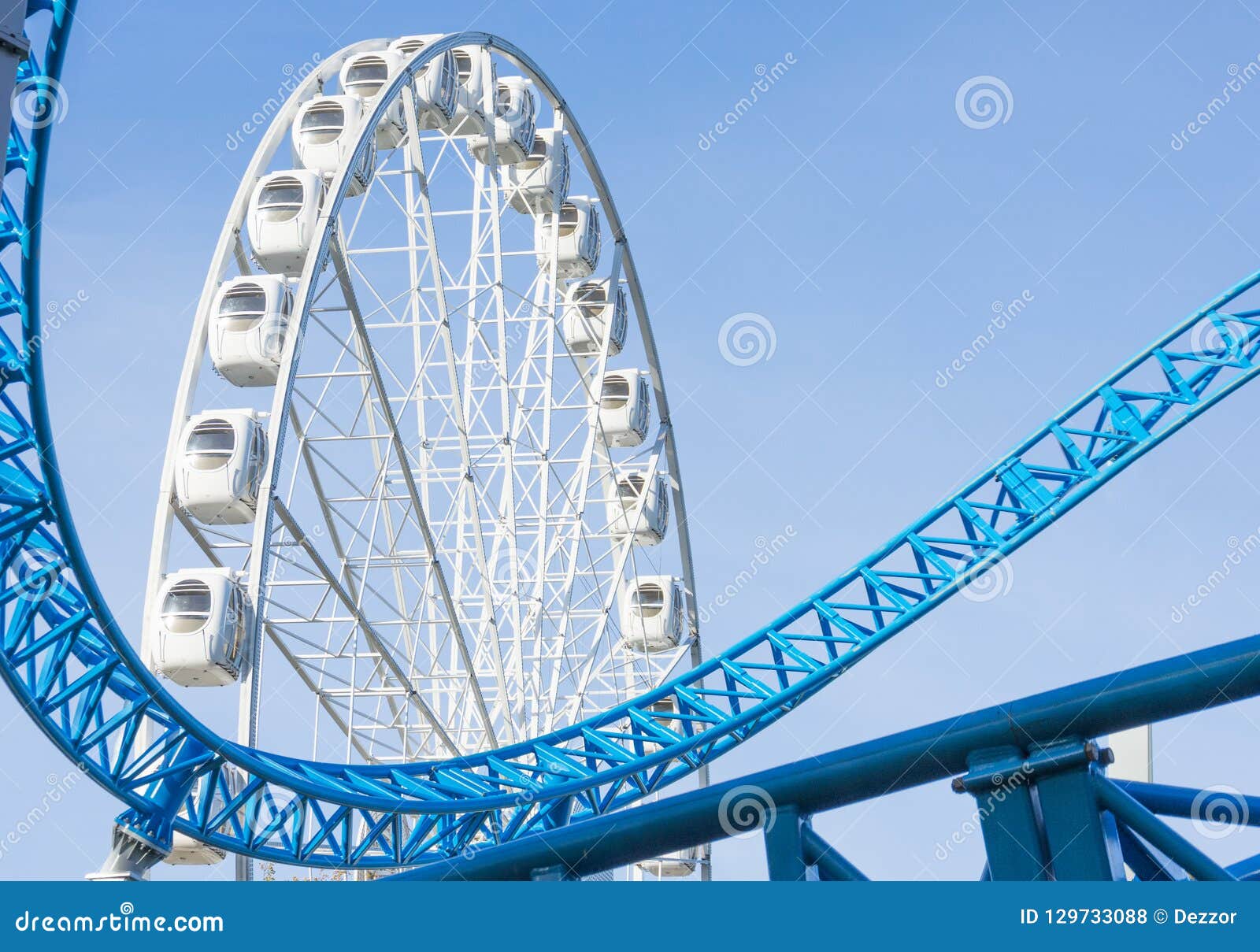 Ferris Wheel and Loop Turn on a Blue Roller Coaster in an Amusement Park. Stock Photo - Image of ...