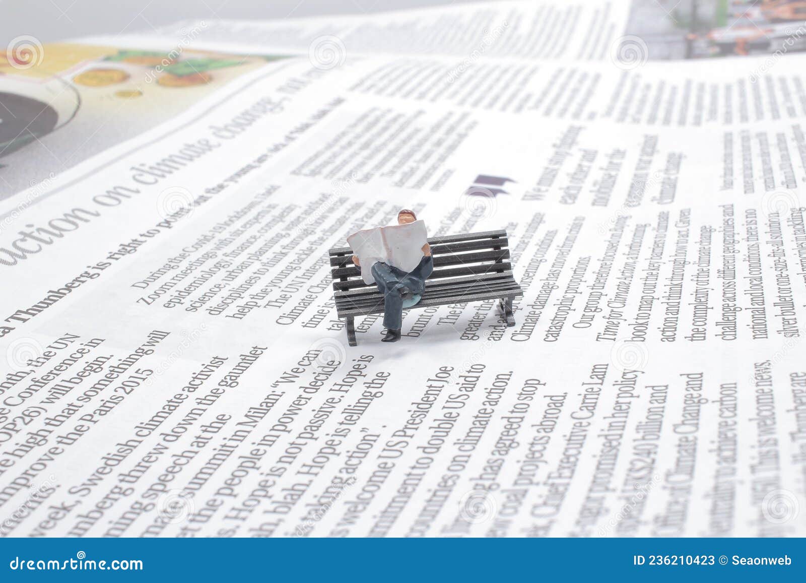 A Figure of a Man Reading a Newspaper while on a Full Size Newspaper ...