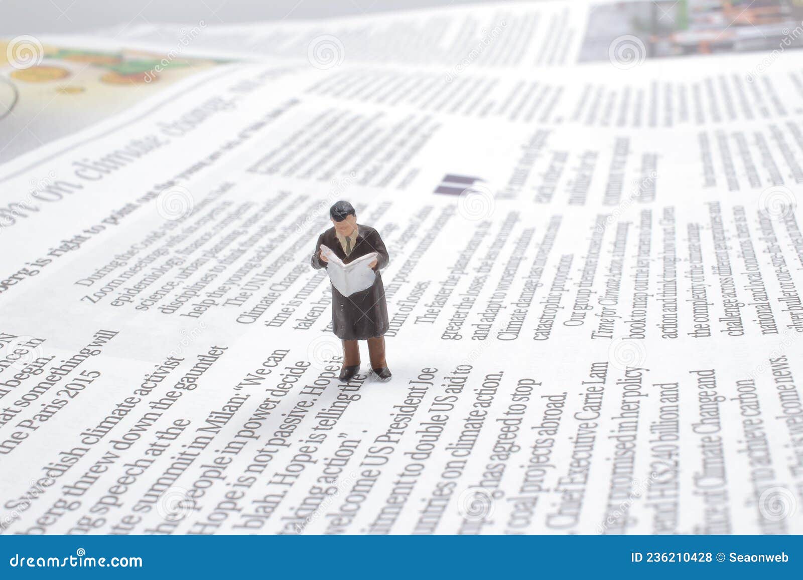 A Figure of a Man Reading a Newspaper while on a Full Size Newspaper ...