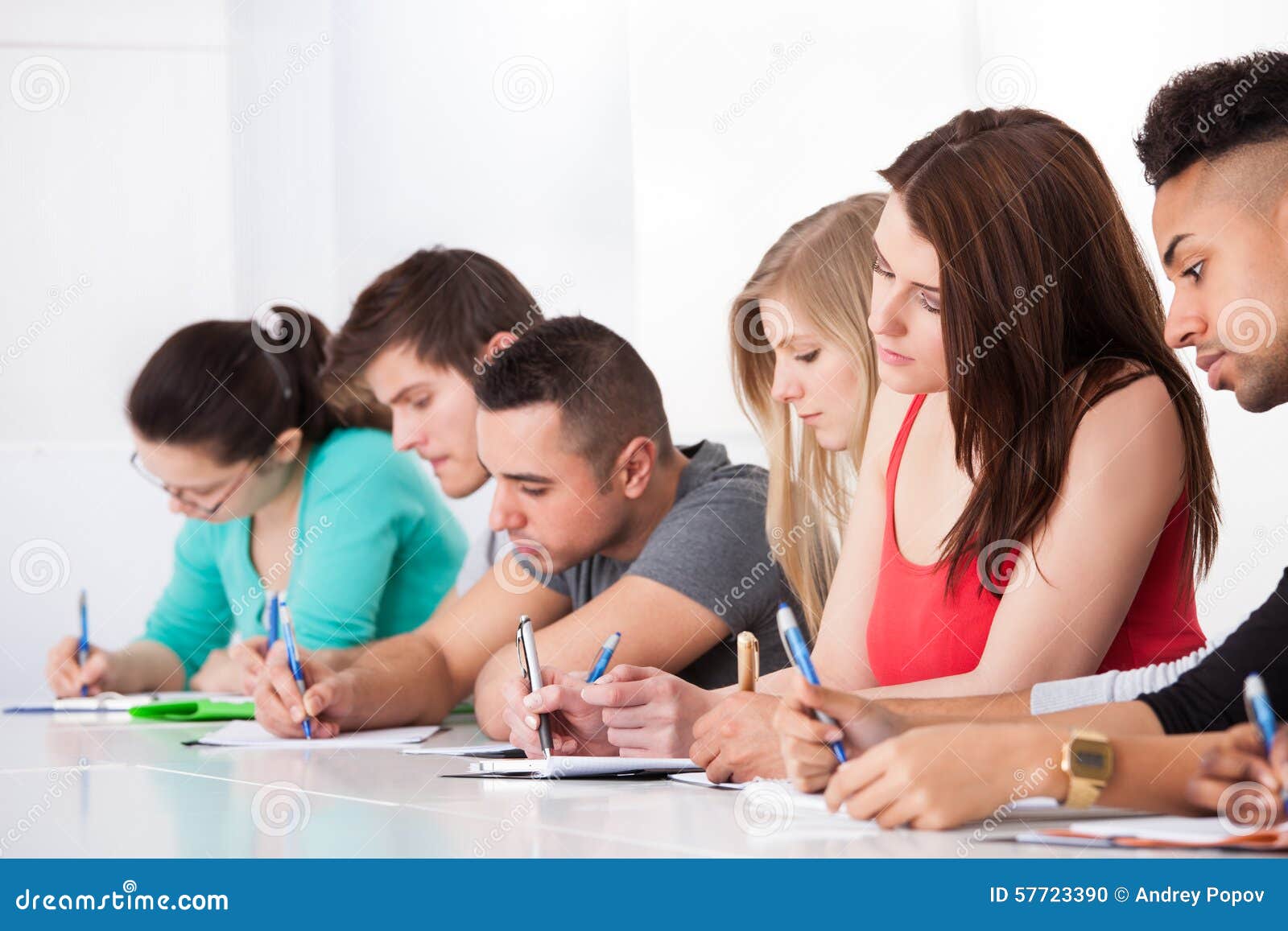 Fila De Los Estudiantes Universitarios Que Escriben En El Escritorio ... Fila De Los Estudiantes Universitarios Que Escriben En El Escritorio ...