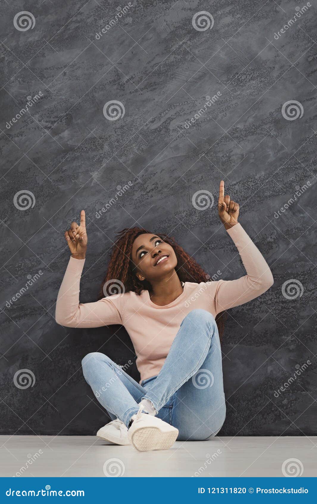 Fille Africaine Heureuse Sasseyant Sur Le Plancher Et Dirigeant Des