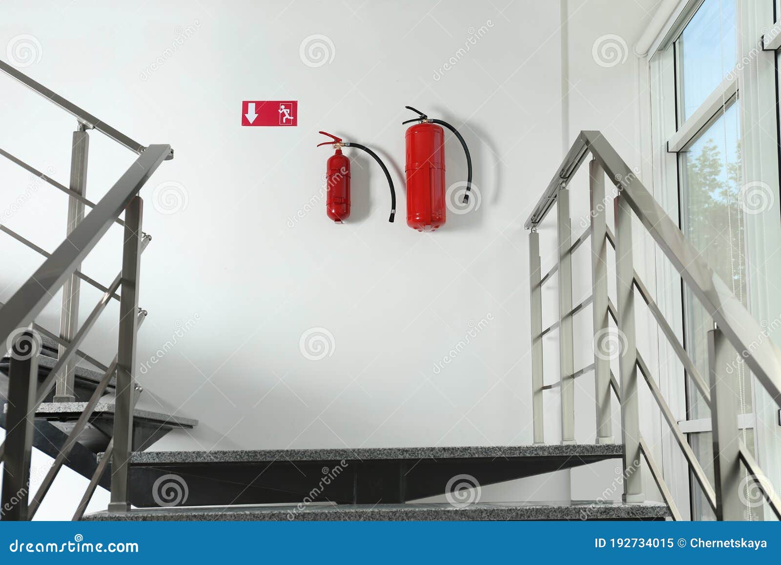 Fire Extinguishers and Emergency Exit Sign on Wall Near Staircase ...