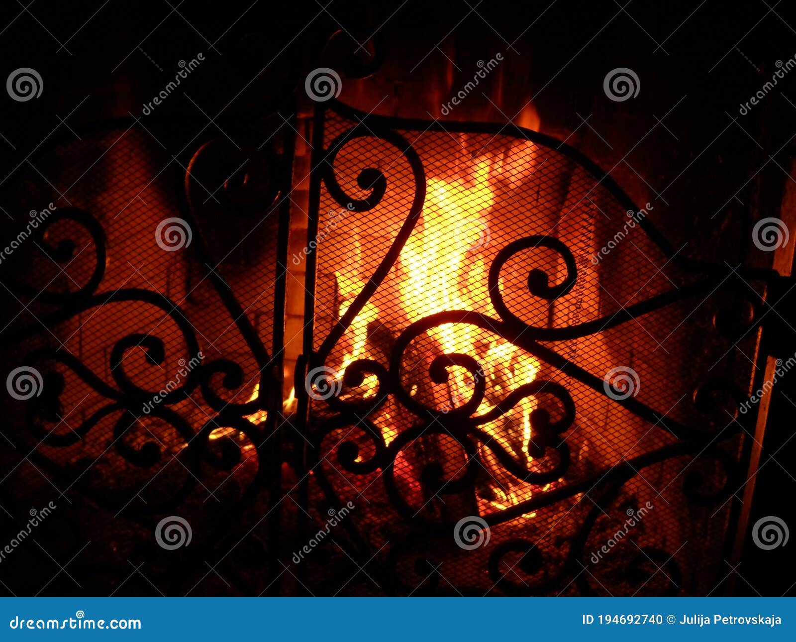 Fire in the Fireplace Behind a Beautiful Wrought Iron Grate with Curls ...
