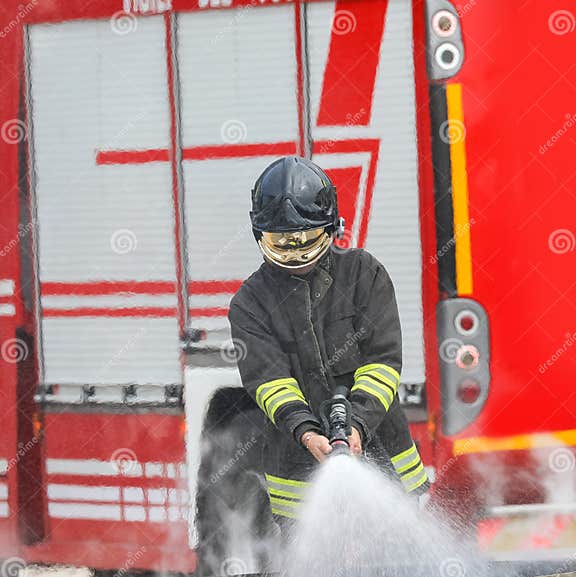 Firefighter with Helmet and Protective Visor while Extinguishing a Fire ...