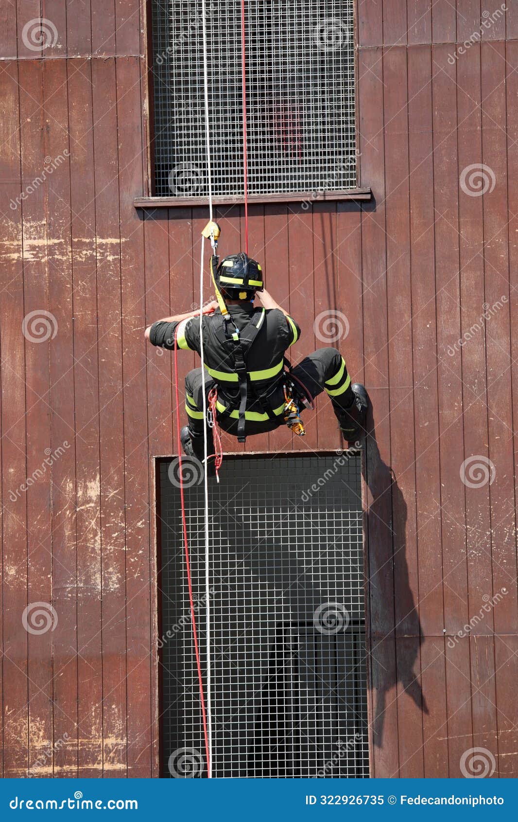 Firefighter in Helmet and Uniform Rappelling Down Building during Fire ...