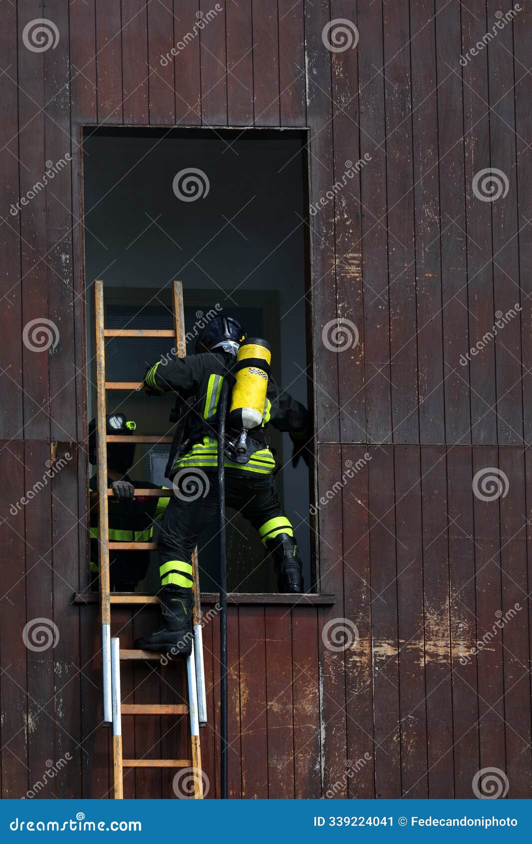 Firefighter with an Oxygen Tank Climbing a Ladder during a Training ...