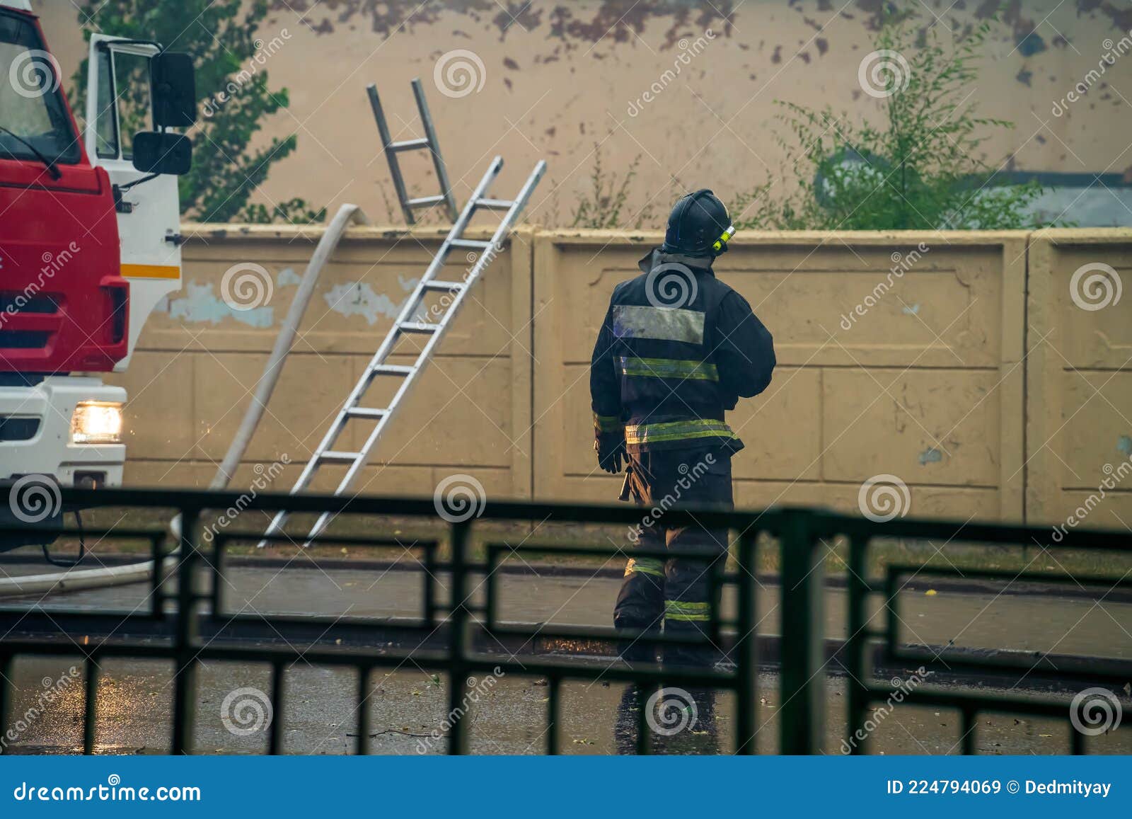 Firefighter Rear View at Wall with Ladders and Fire Engine at Scene of ...