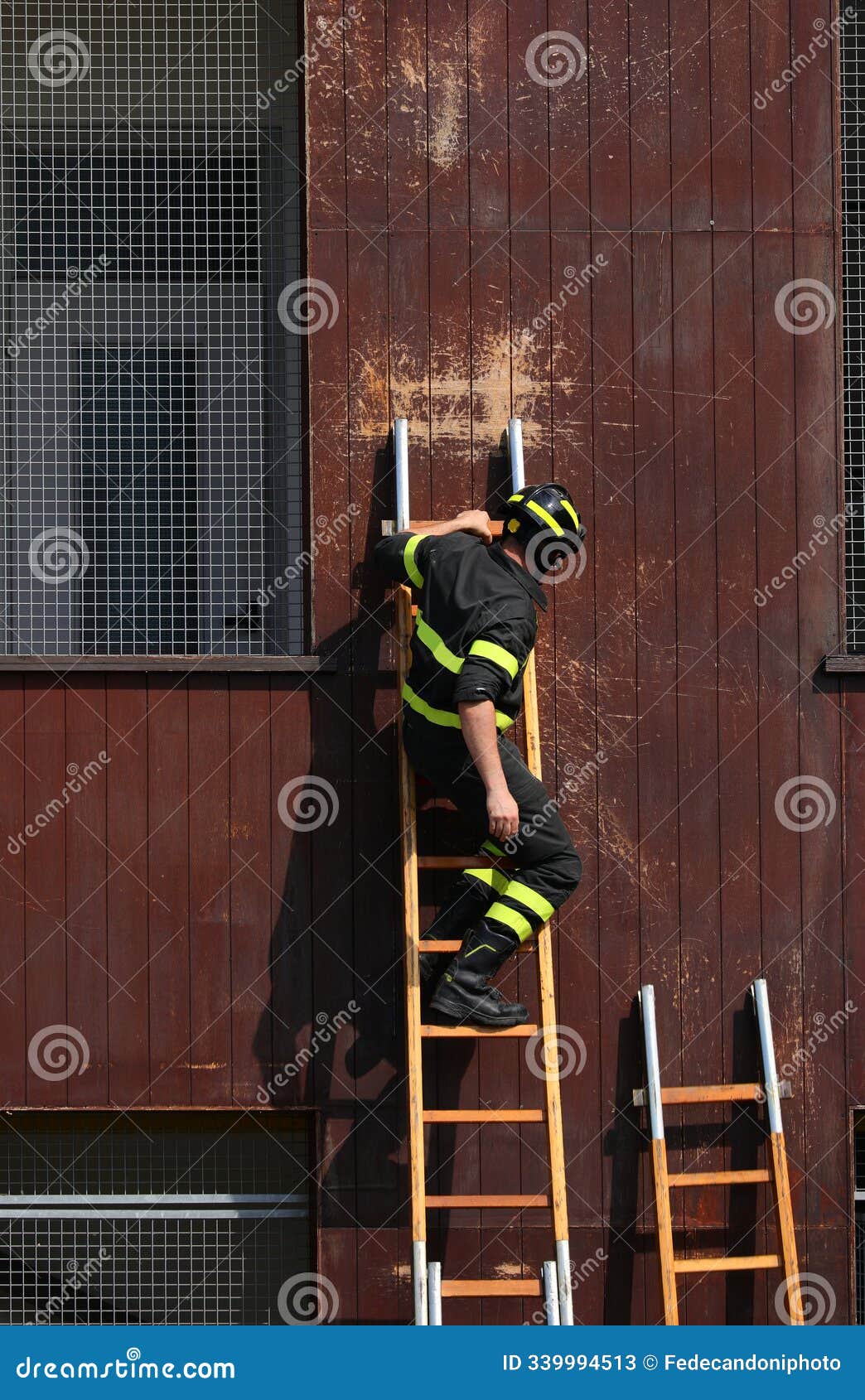 Firefighter in a Uniform and Helmet is Setting Up a Ladder during a ...
