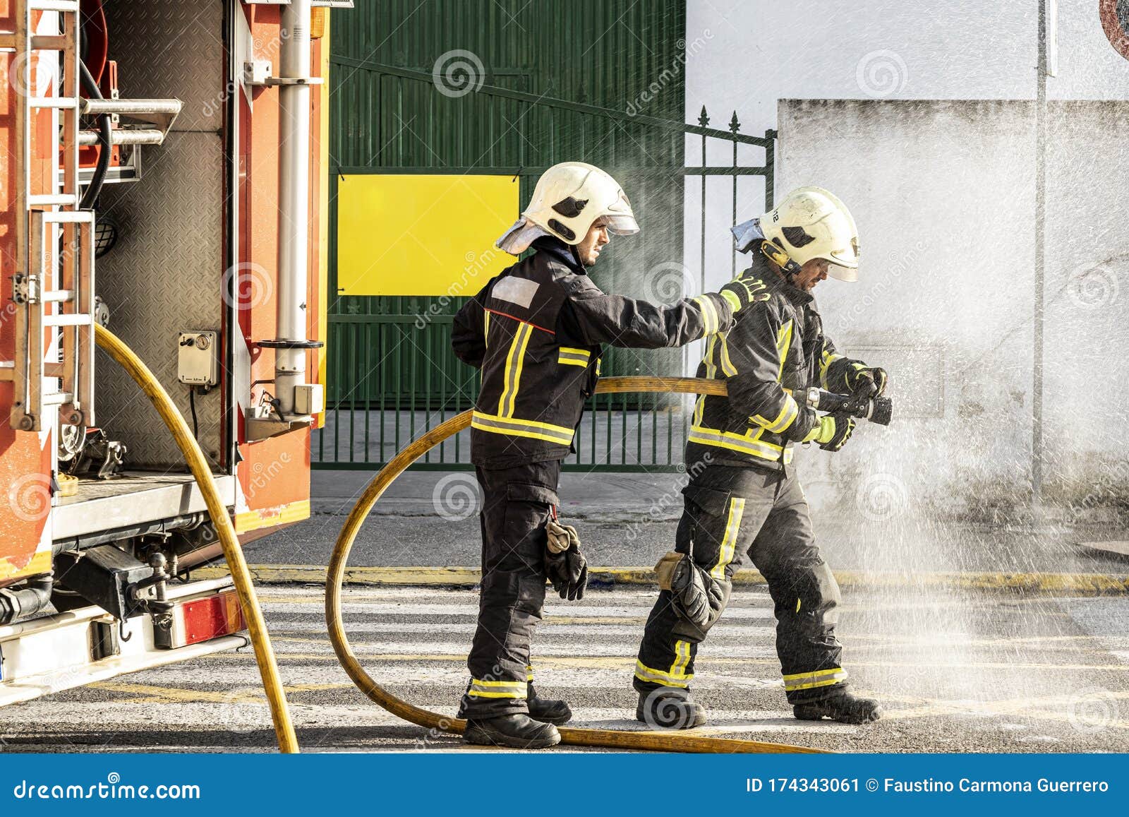 Firefighters with a Water Hose Pulling Water To Put Out a Fire Stock ...