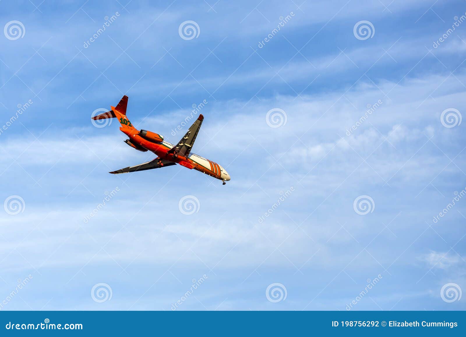 Firefighting Jet Plane Number 102 Flying Against a Blue Sky with Clouds ...