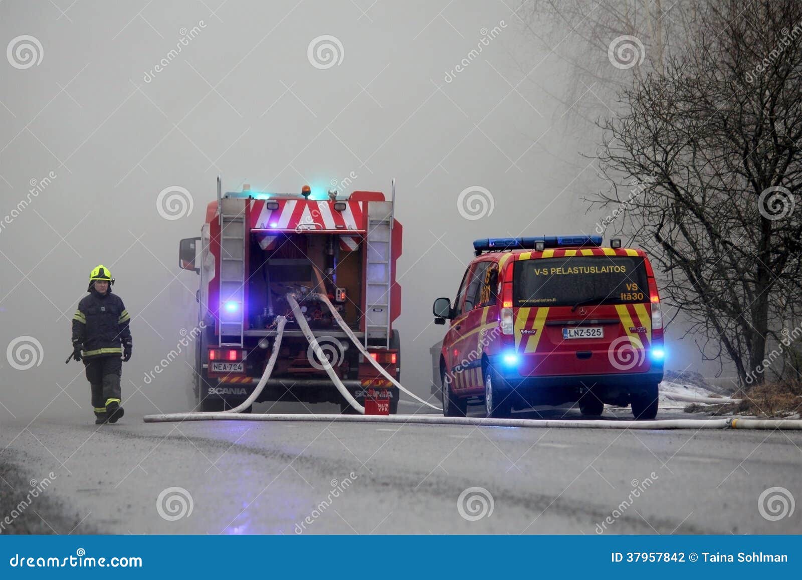 Fireman Emerging from Smoke with Fire Trucks on the Street Editorial ...