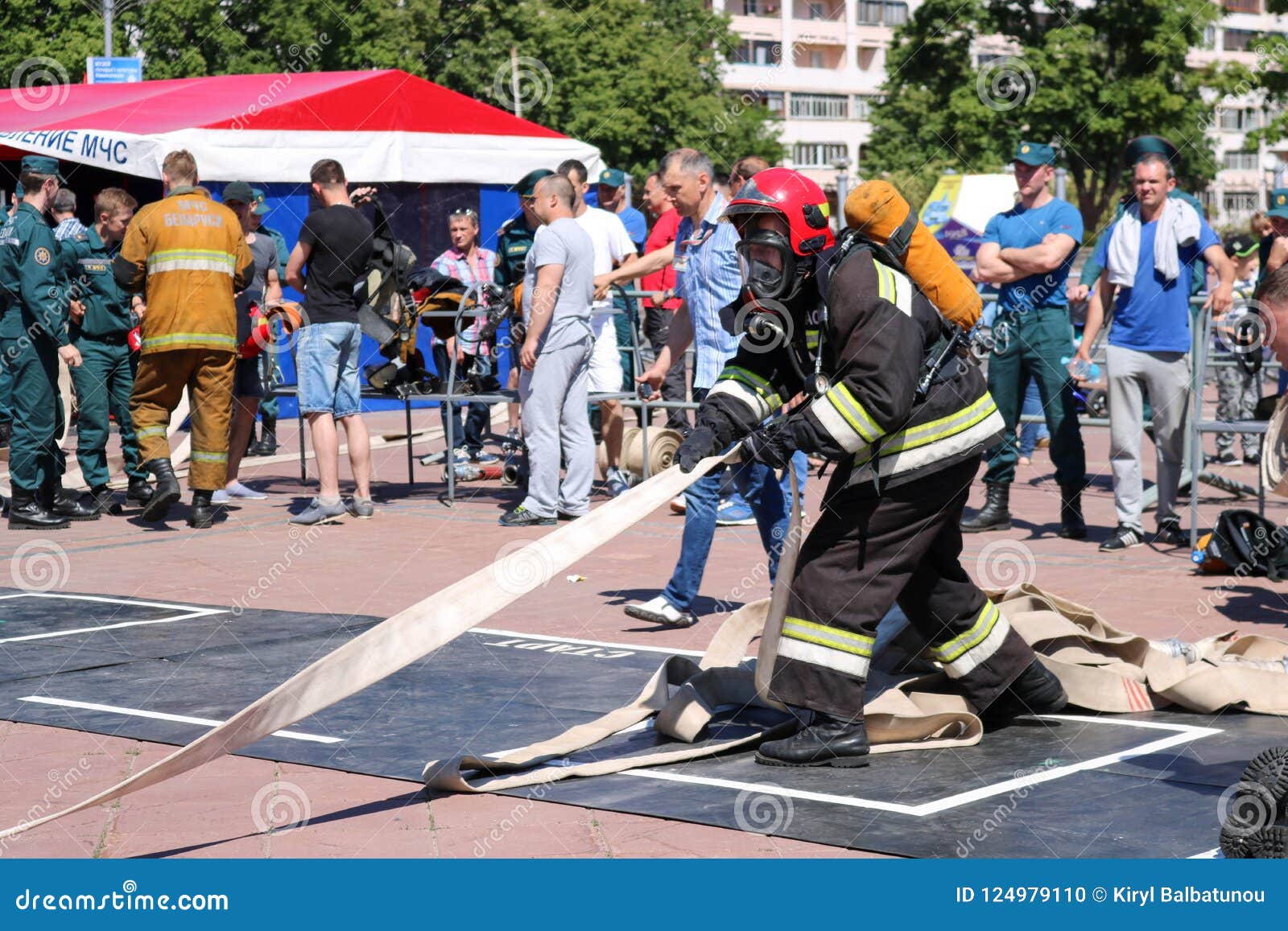 A Fireman in a Fireproof Suit and a Helmet Holding a Fire Hose at a ...