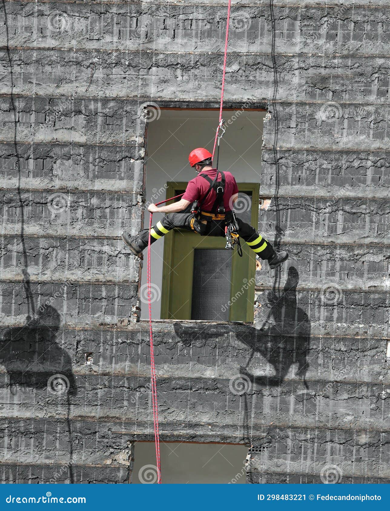 Fireman in Harness with Rope Climbing Over a Destroyed Building ...