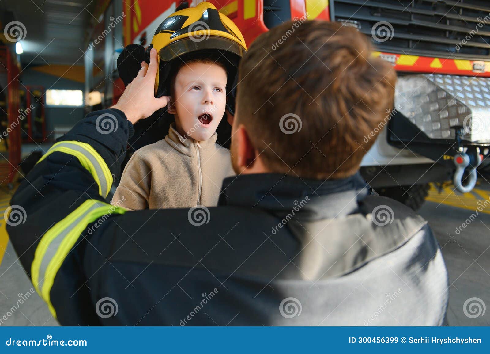 A Fireman Shows His Work To His Young Son. a Boy in a Firefighter& X27 ...