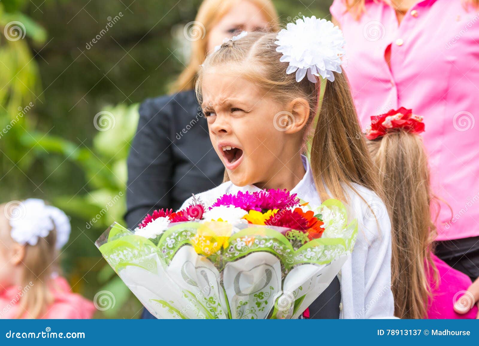 First Grader with Bouquet of Flowers Yawns at School in a Crowd Stock ...