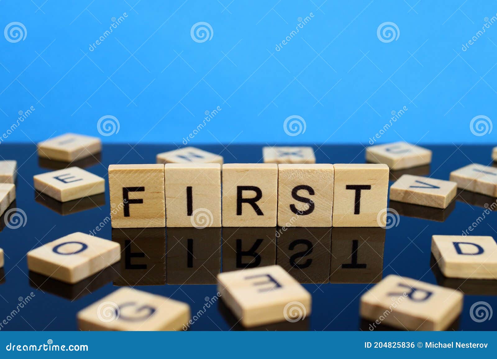 First Word Made of Wooden Letters on a Mirror Surface on a Blue ...