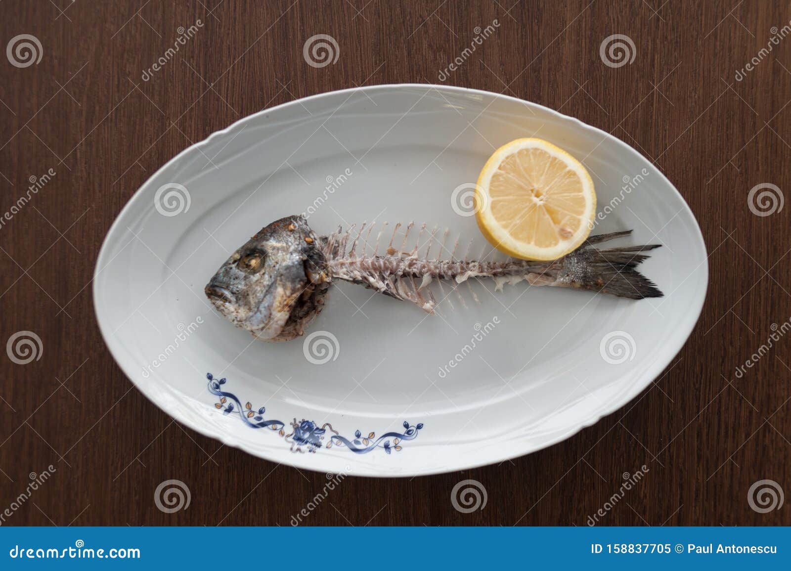 Fish Bone Left Overs with a Sliced Lemon on a White Oval Plate. Stock ...