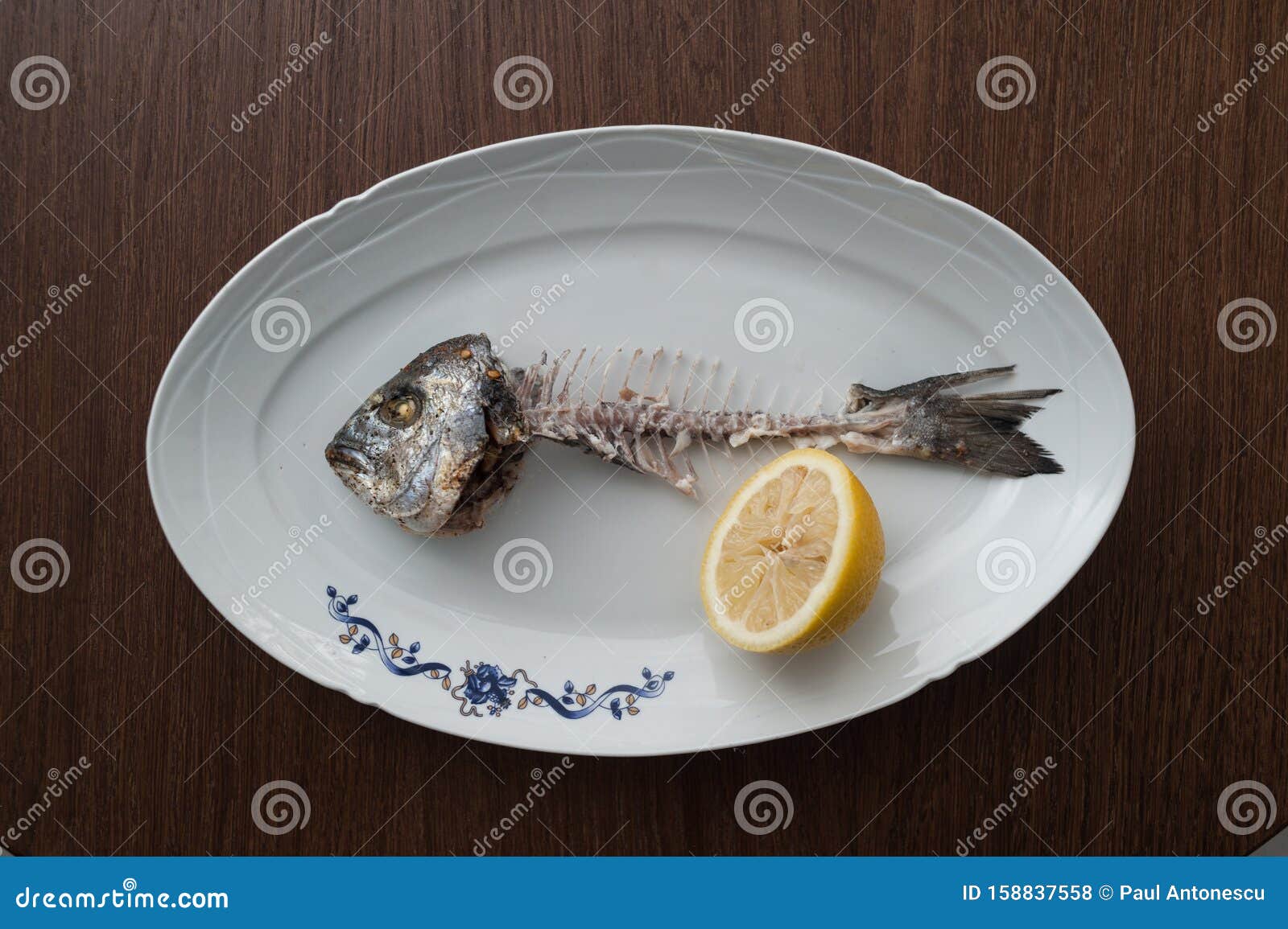 Fish Bone Left Overs with a Sliced Lemon on a White Oval Plate. Stock ...