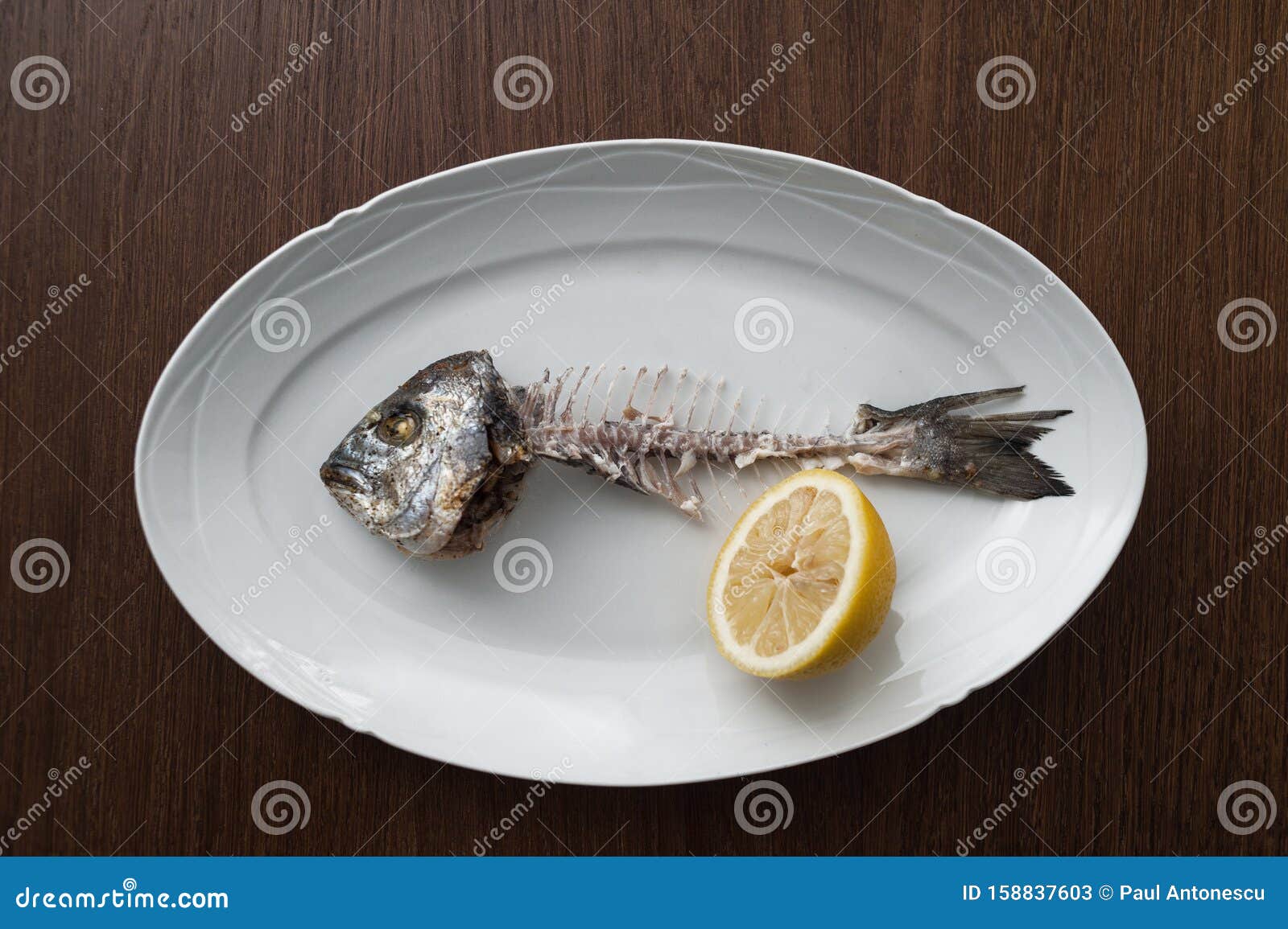 Fish Bone Left Overs with a Sliced Lemon on a White Oval Plate. Stock ...