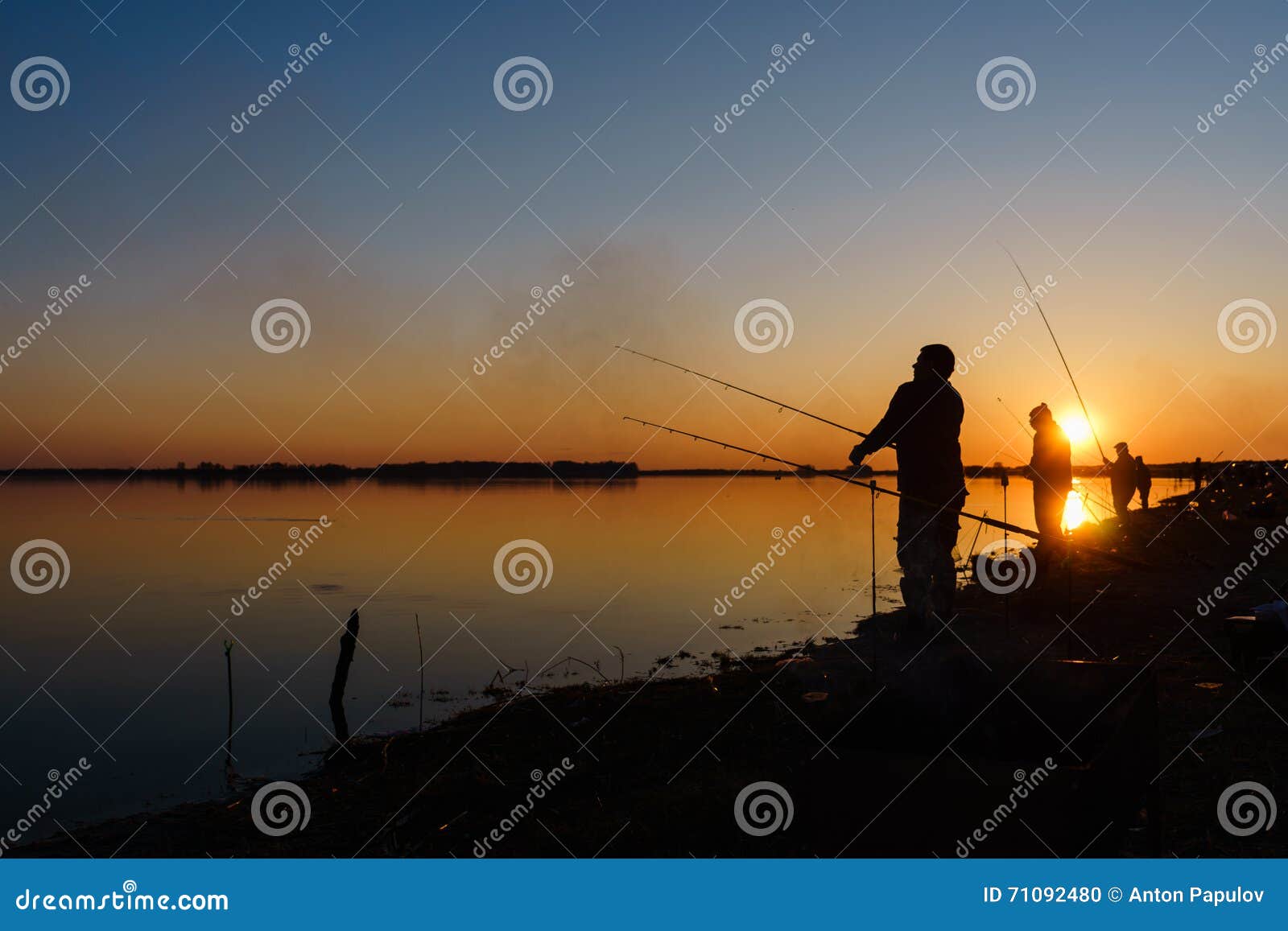 Fisherman Catches Fish by Spinning on the Lake at Sunset Stock Photo ...
