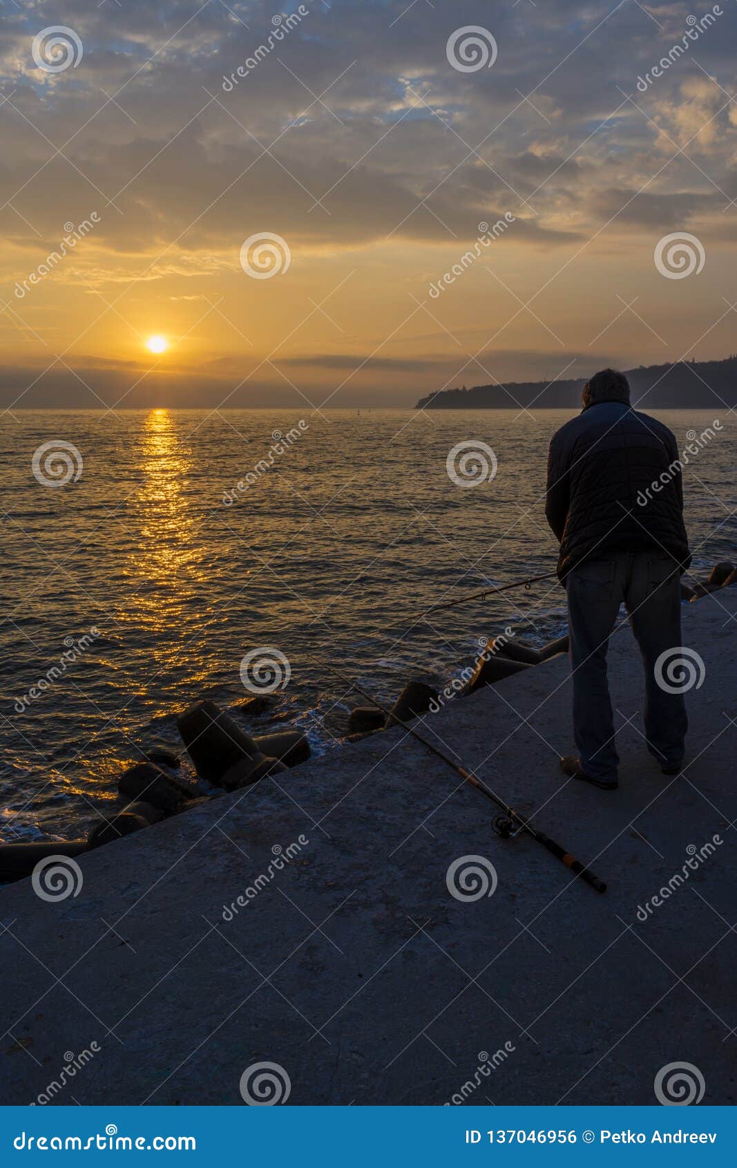 A Fisherman Catching Fish at Sunrise at a Seaport. Stock Photo - Image ...