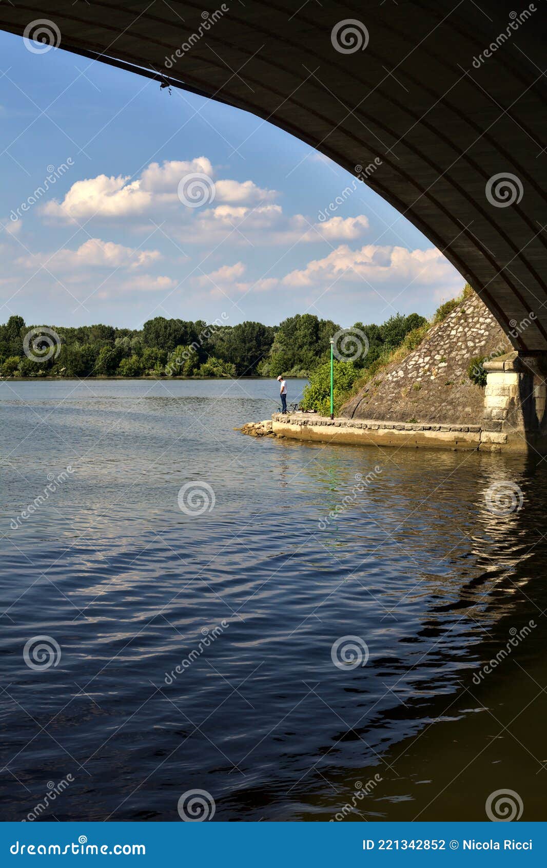 Fisherman on the Shore of a Lake Under a Bridge on a Sunny Day in ...