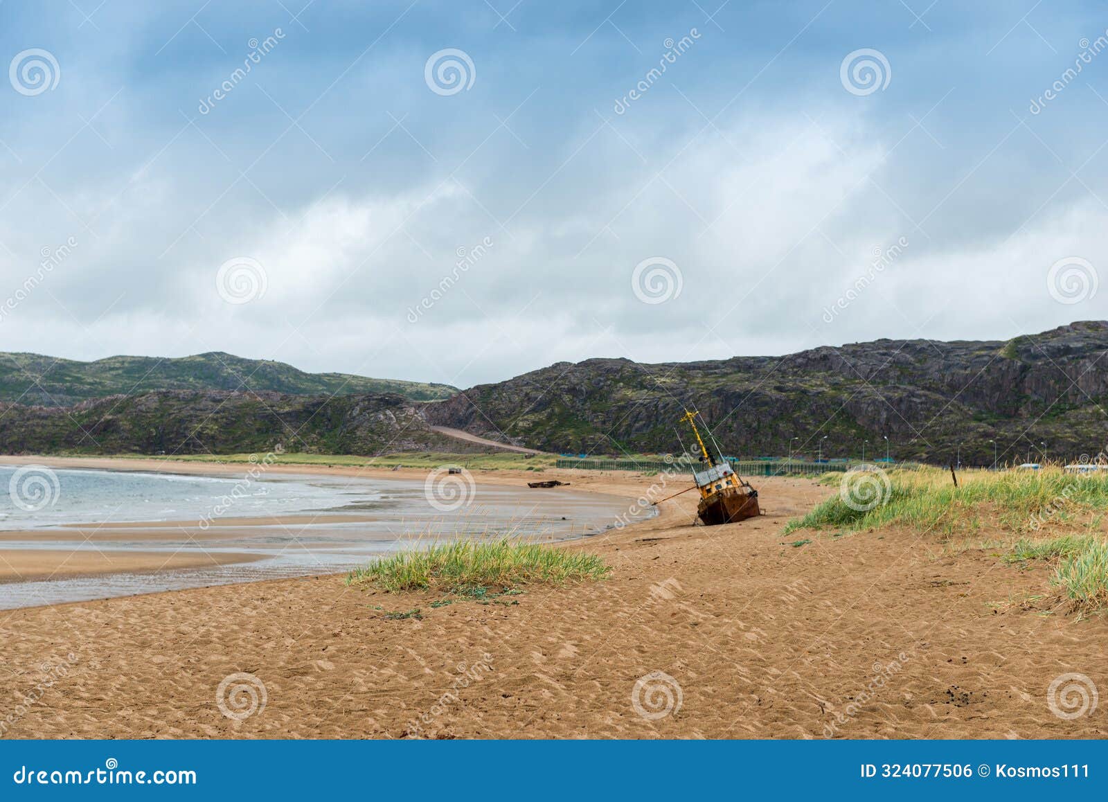 A Fishing Boat with a Hole Washed Up on an Empty Beach Stock Photo ...
