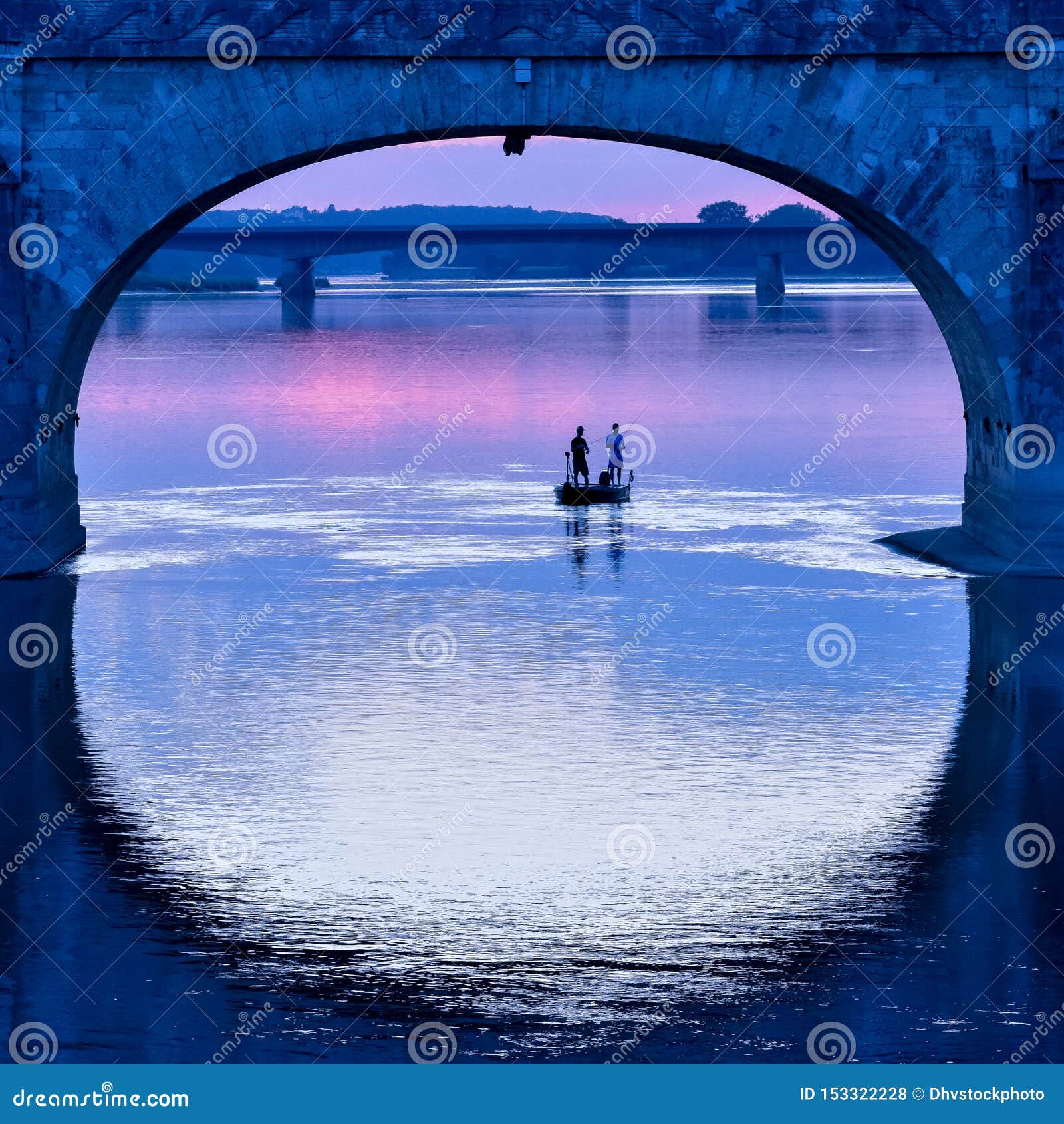 Fishing Boat Under the Arch of a Bridge in a Colorful Sunset Stock ...