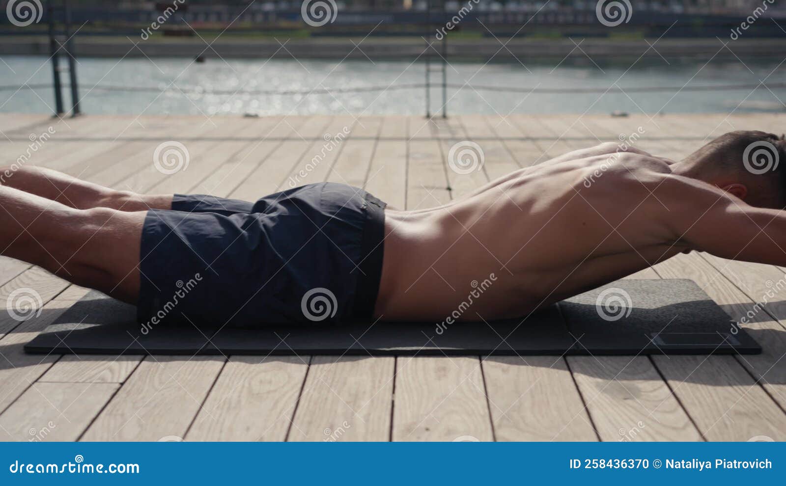 A Fit Caucasian Man Does Superman Back Extensions on a Black Mat ...