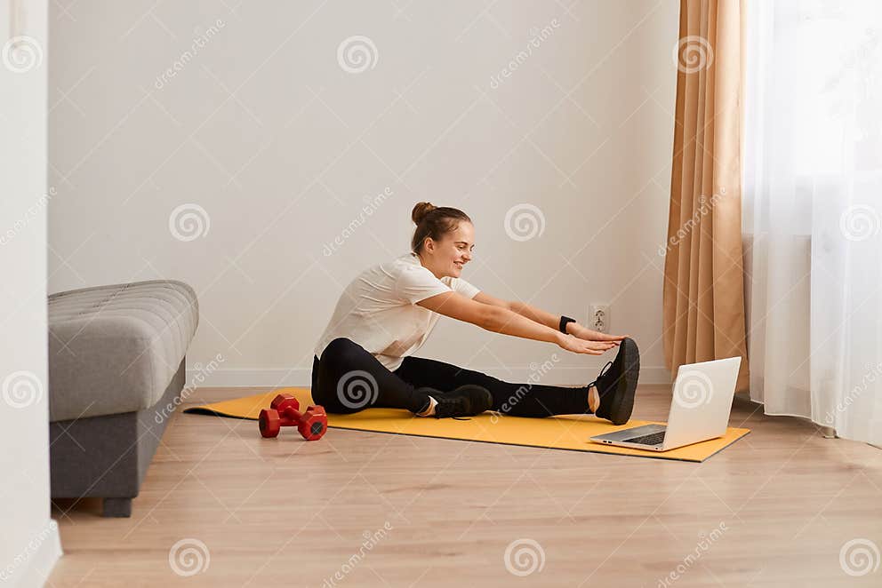 Fit Gymnast Woman With Hair Bun Sitting On Mat With Spread Legs And
