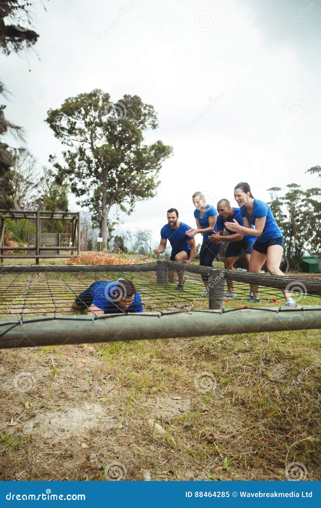 Fit Man Crawling Under the Net during Obstacle Course while Fit People ...