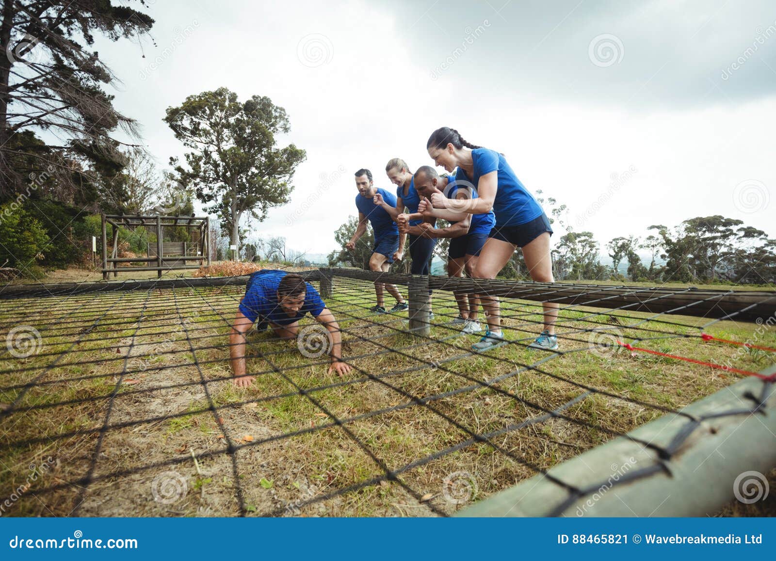 Fit Man Crawling Under the Net during Obstacle Course while Fit People ...