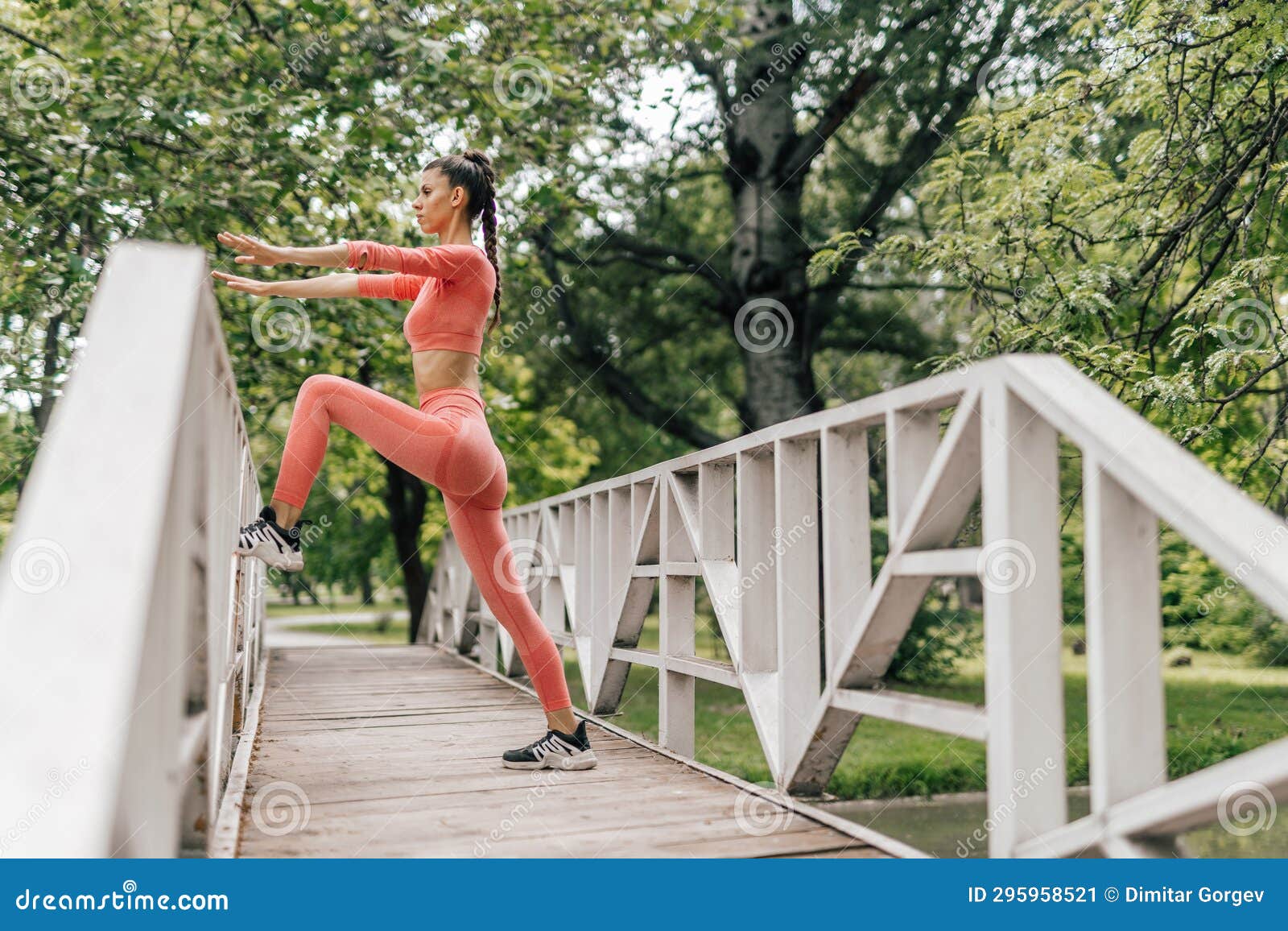 Fit Slim Girl Stretching Her Legs While Standing On A Bridge In The