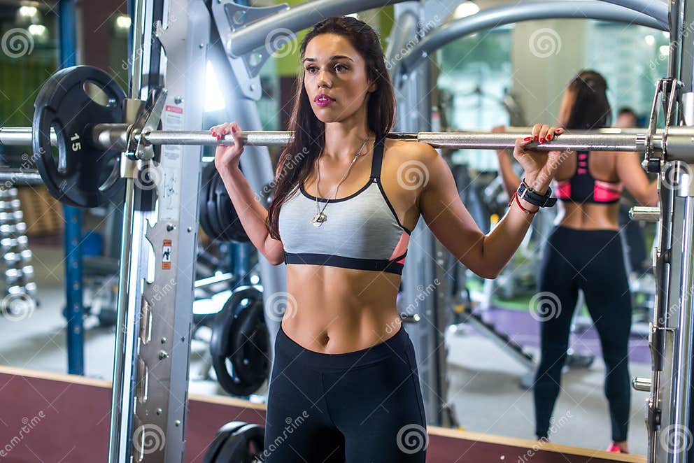 Fit Woman Doing Squats With The Barbell Smith Machine In The Gym Stock