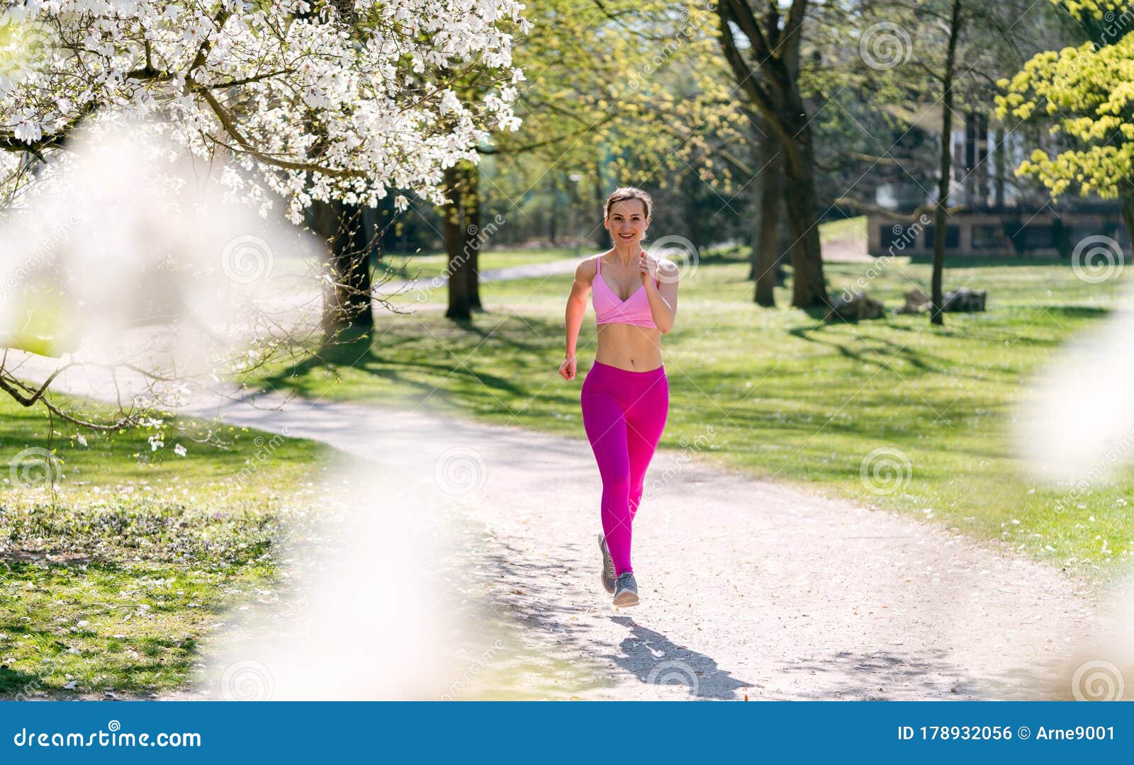 Fit Woman Running Down a Path during Spring Seen through Blossom Stock ...