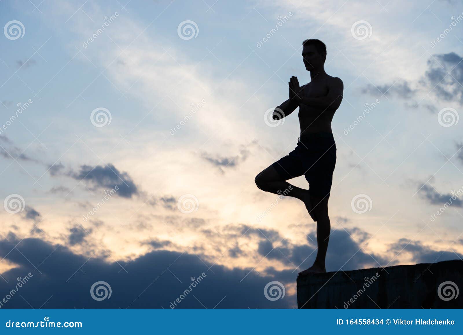Fit Young Man Practices Sun Salutation Yoga on the Edge of Cliff at ...