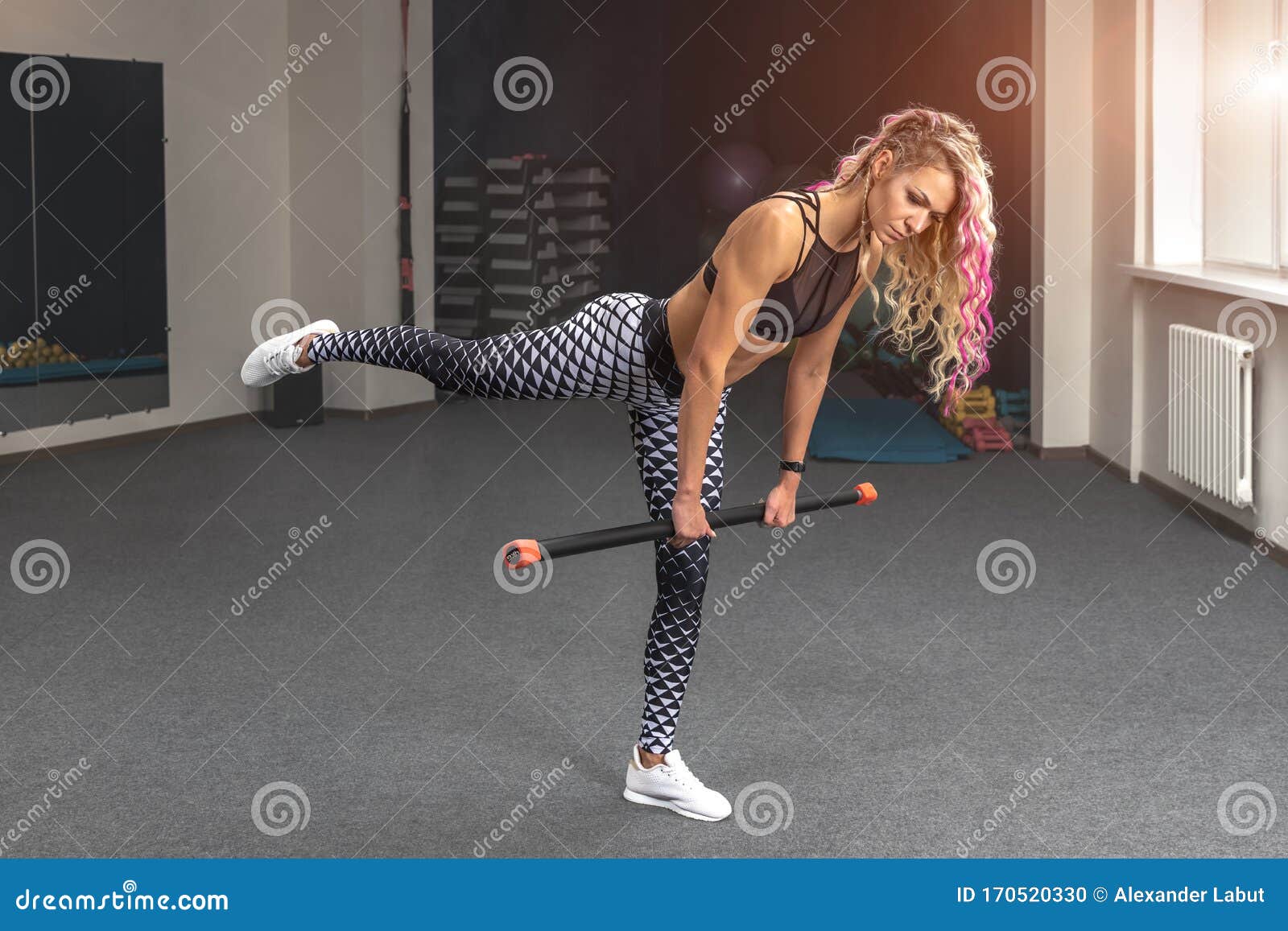 Fitness Woman With Blond And Pink Long Hair Doing Exercises With Gymnastic Stick Blurred