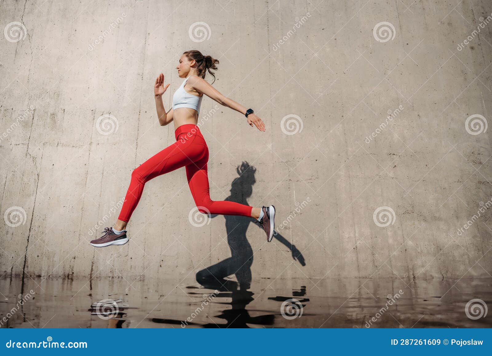 Fitness Woman Running in Front of Concrete Wall Casting Shadow. Imagen ...