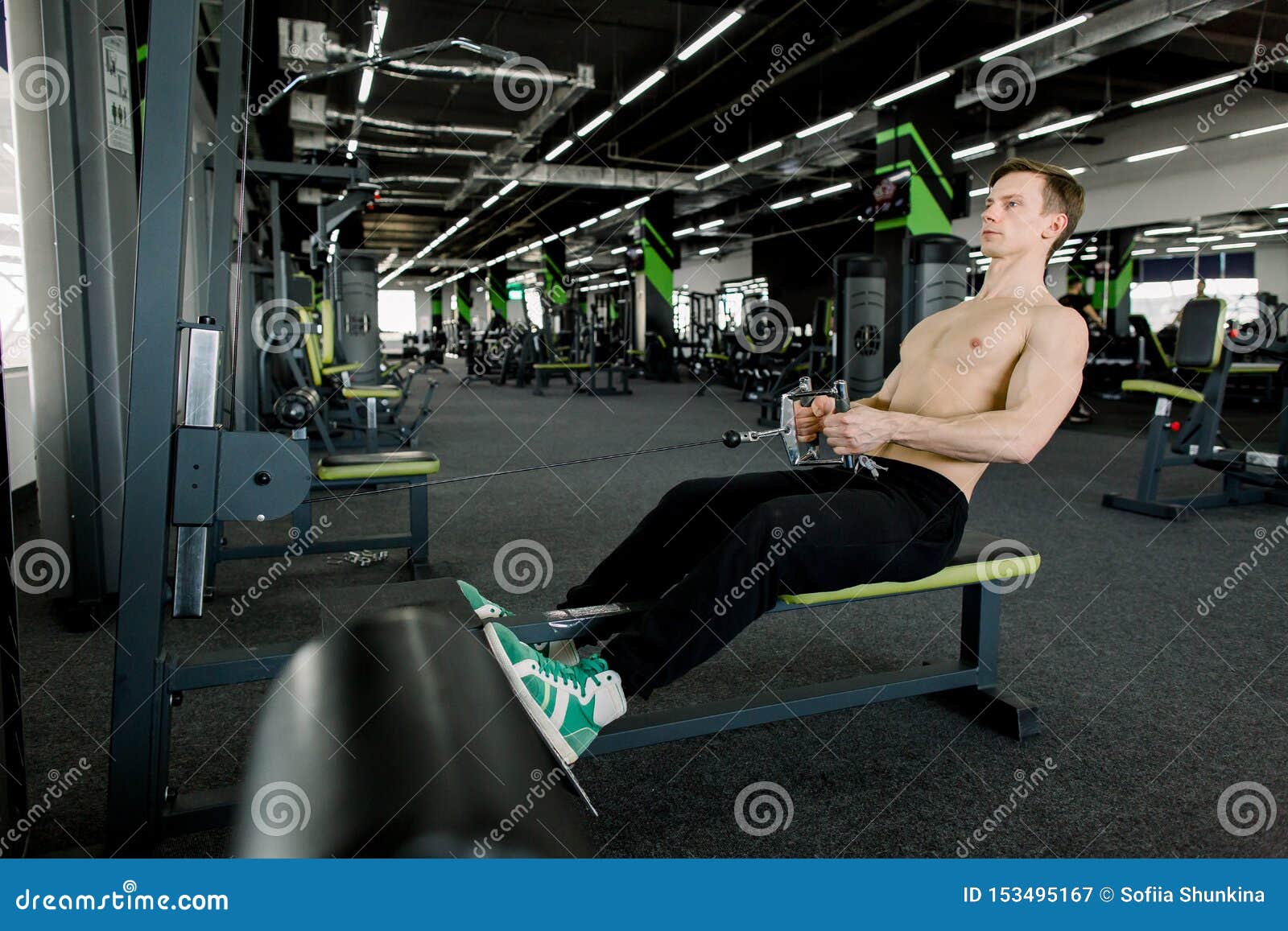 Fitness Young Man Using Rowing Machine in the Gym. Sporty Man in the ...