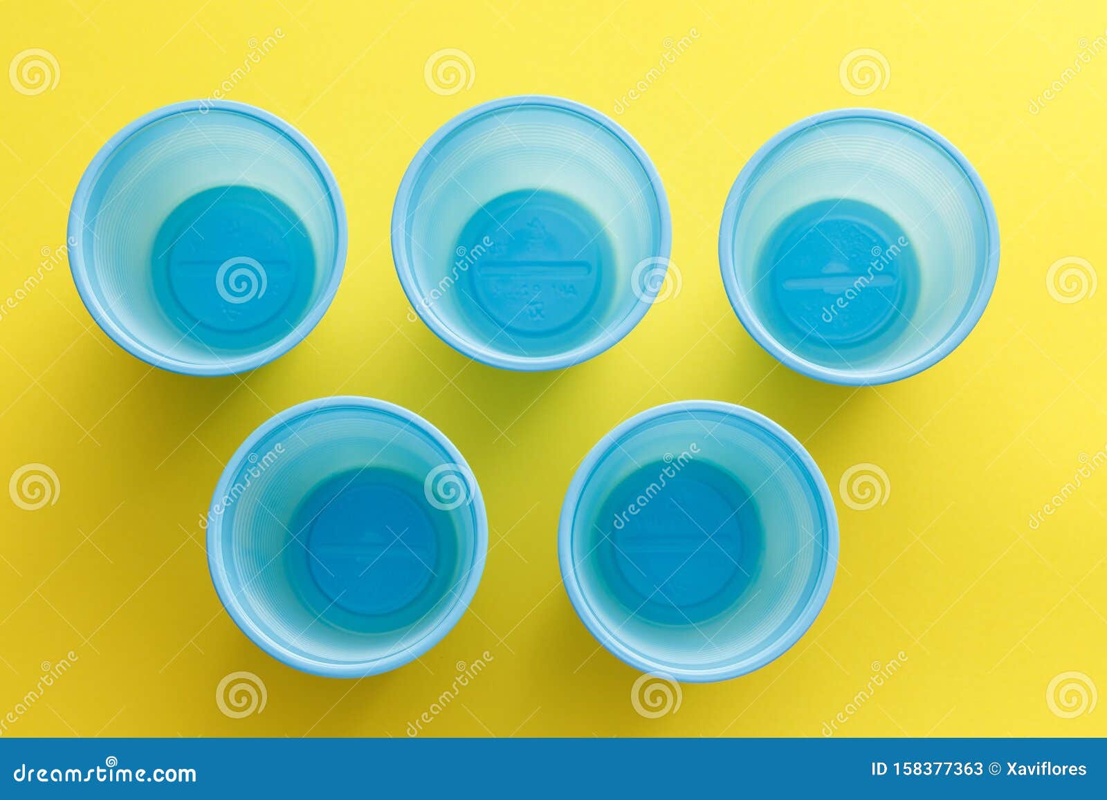 Five Empty Blue Plastic Disposable Cups Over a Yellow Background Stock ...