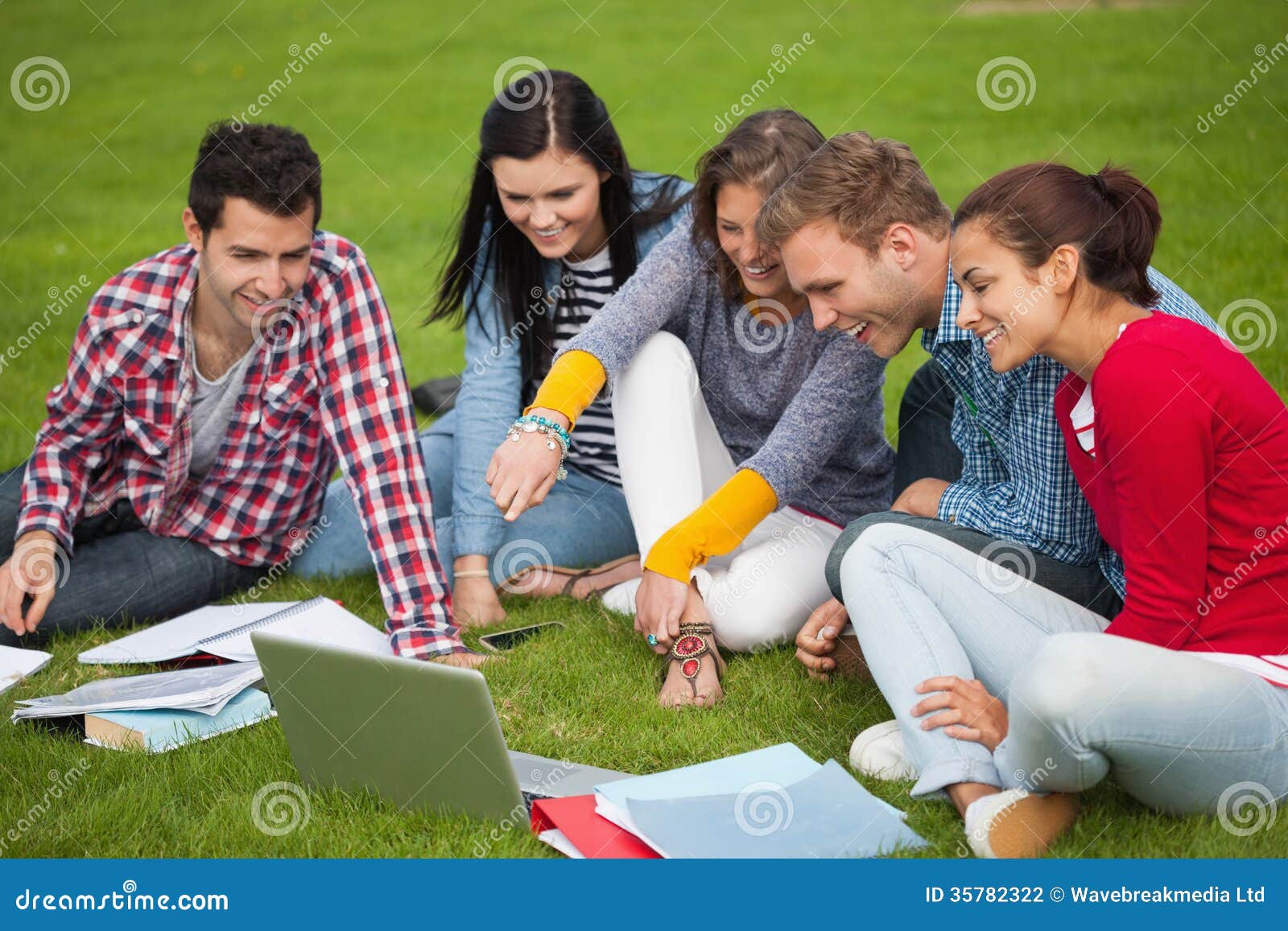 Five Students Sitting on the Grass Pointing at Laptop Stock Photo ...