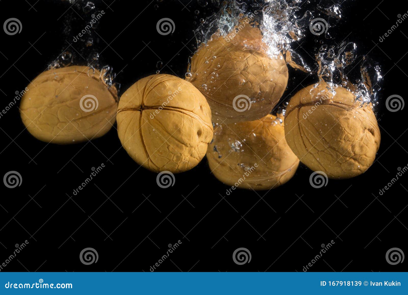 Five Walnuts Falls into the Water with Splashes and Bubbles on a Black ...