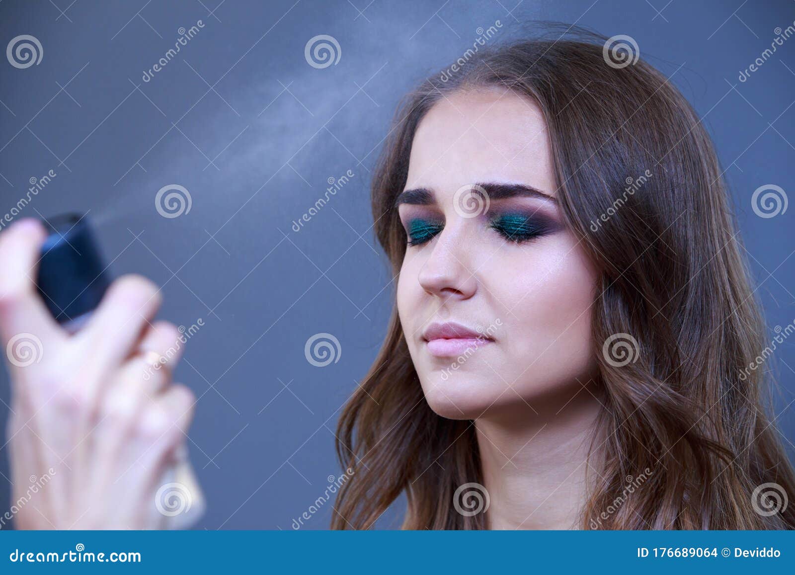 Fixing makeup with a spray stock photo. Image of face - 176689064