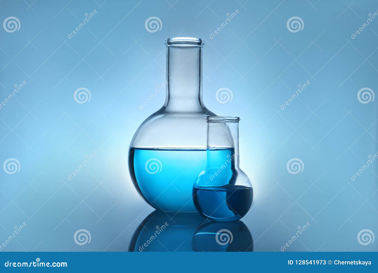 Flasks with Liquid on Table Against Color Background Stock Image ...