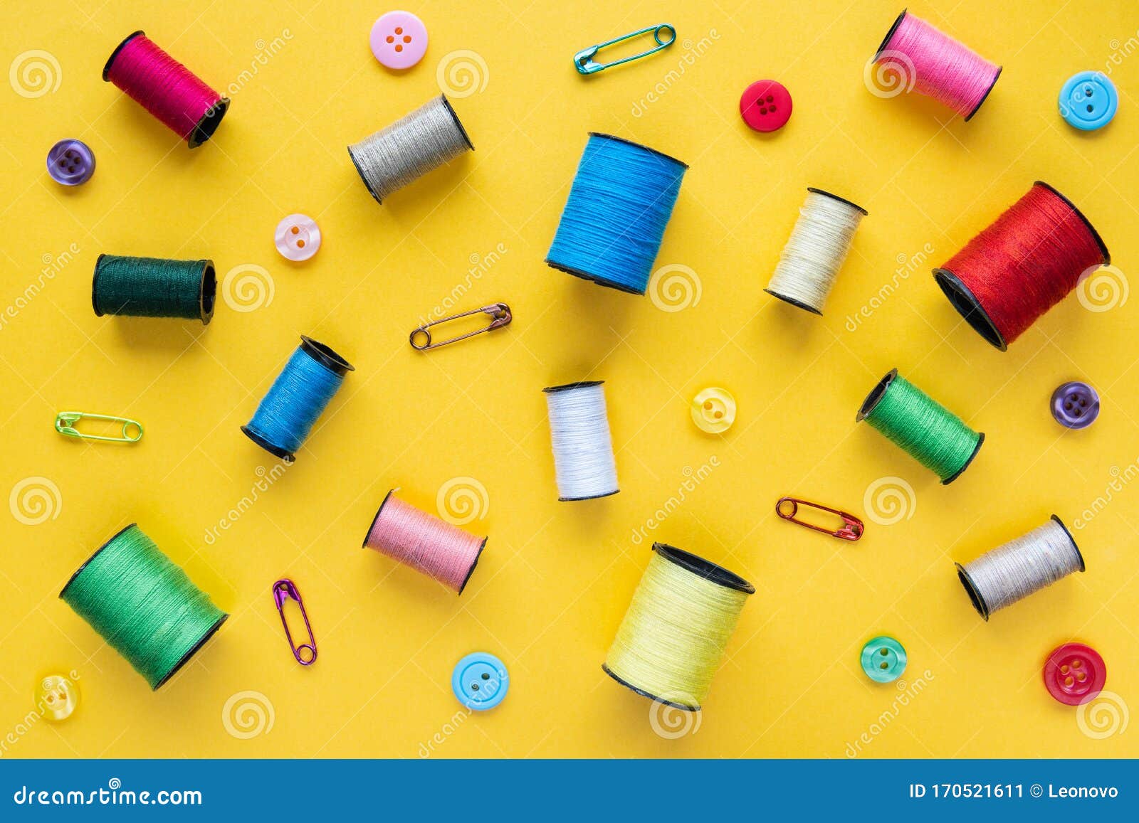 Spools of Colored Thread, Buttons and Safety Pins on Yellow Background ...