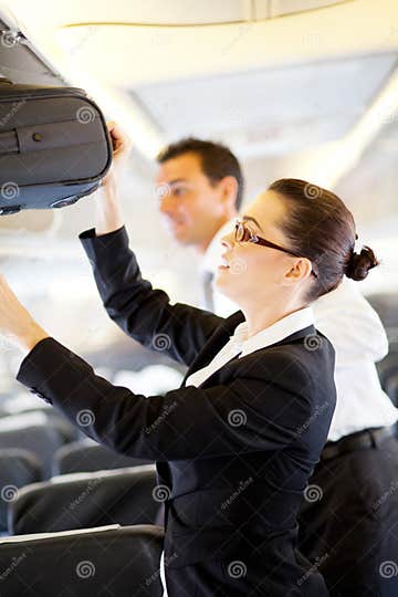 Flight Attendant Helping Passenger Stock Image - Image of baggage ...