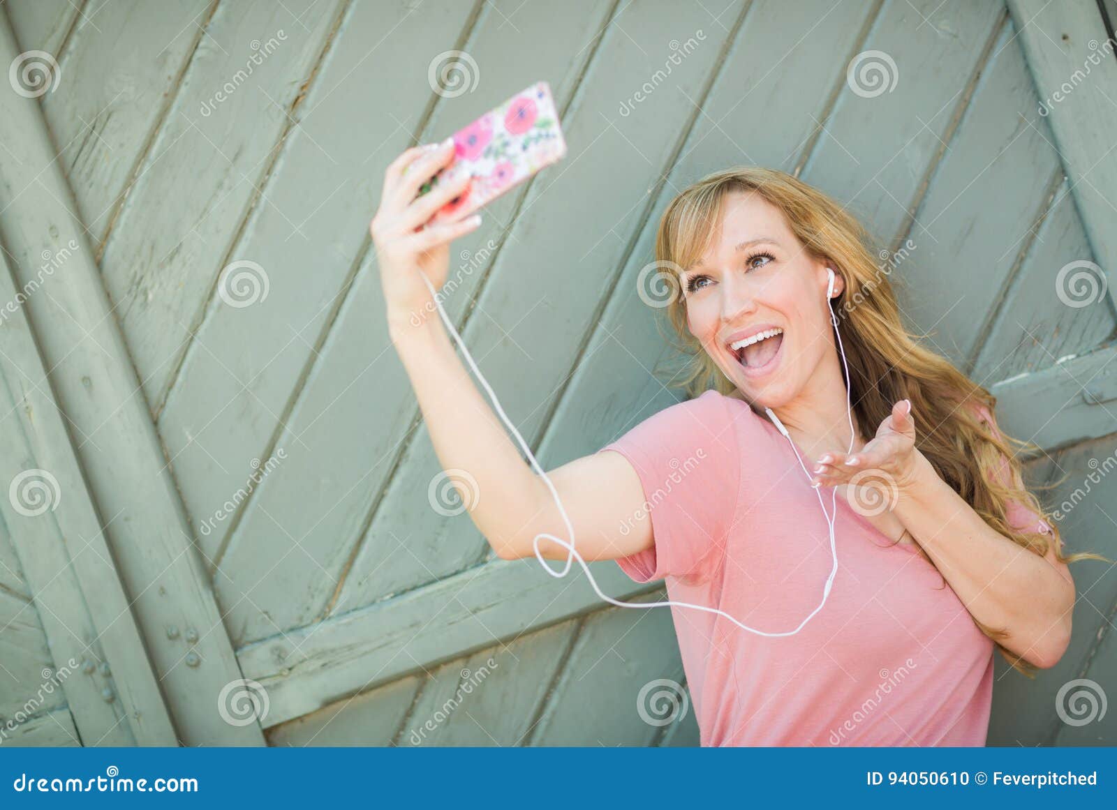 Flirty Young Adult Woman Wearing Earphones Taking a Selfie with Her Sma ... Flirty Young Adult Woman Wearing Earphones Taking a Selfie with Her Sma ...
