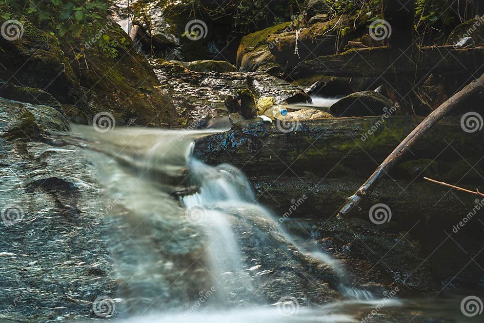 Flowing Waterfall with Plastic Bottle Washed Up on a Rock Stock Photo ...