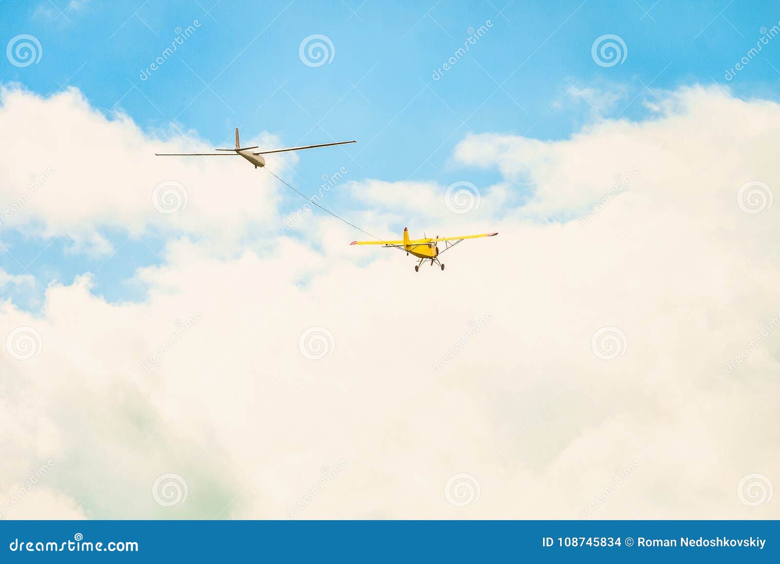 Flying in a Bright Cloudy Sky, a Yellow Small Sports Plane with a Light ...